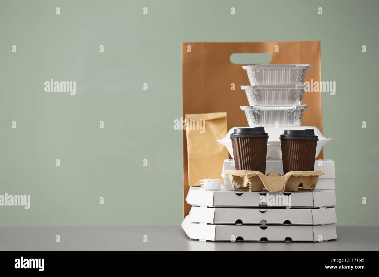 Different packages and carton cups on table against color background ...