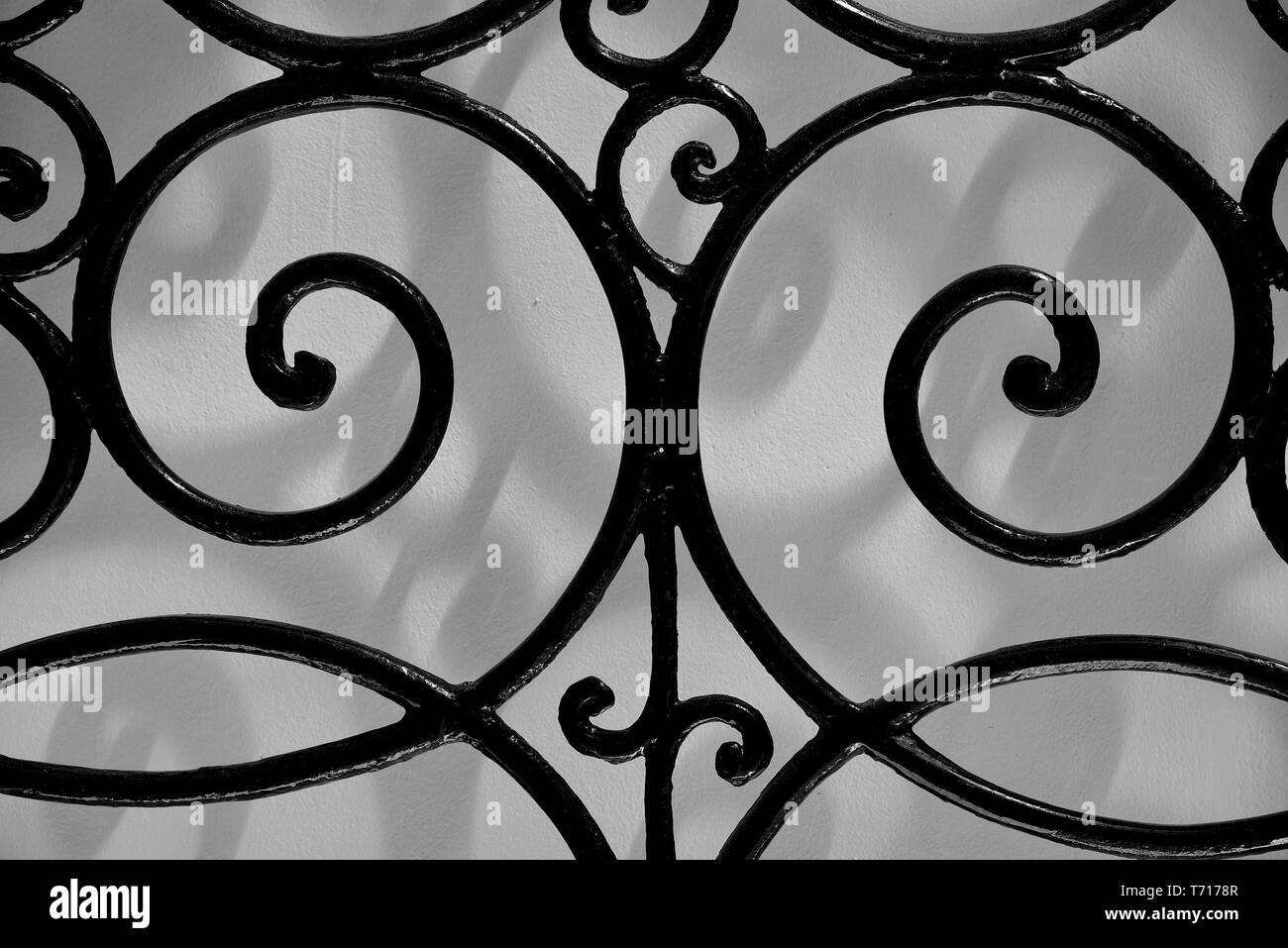 Curved black iron bars casting shadows on wall Stock Photo - Alamy