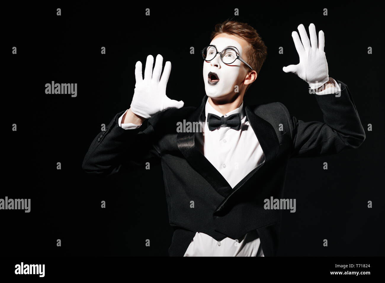 portrait of mime man holding his hands on an invisible wall on black ...