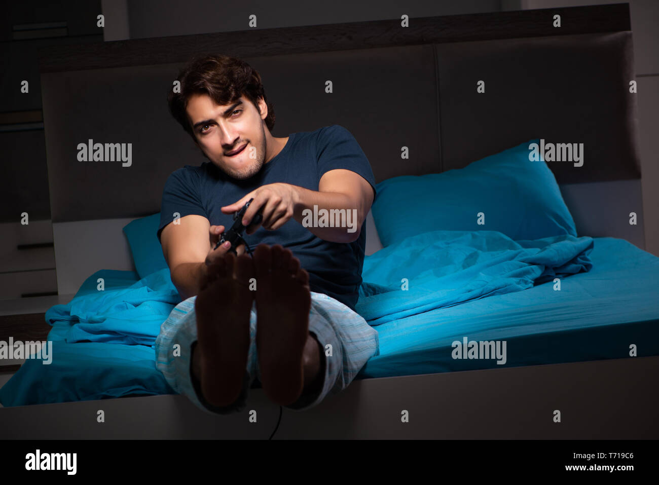 Young man playing computer games at night in bed Stock Photo - Alamy