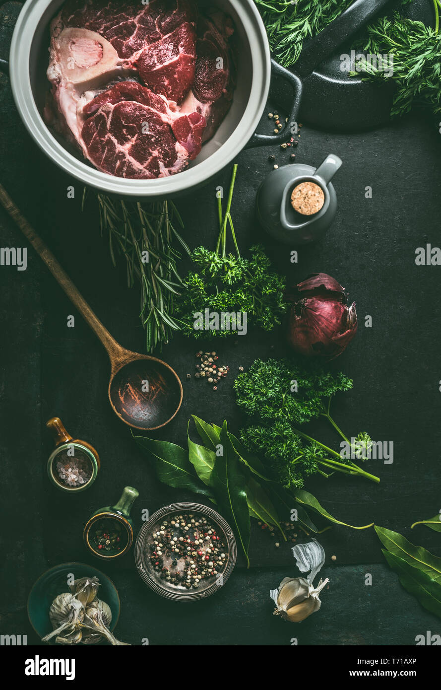 Raw meat with bone in cooking pot on dark kitchen table background with ...