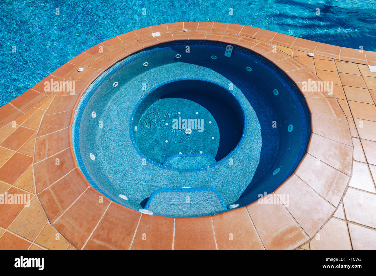 Swimming pool, sun-loungers and palm trees during a warm sunny day ...
