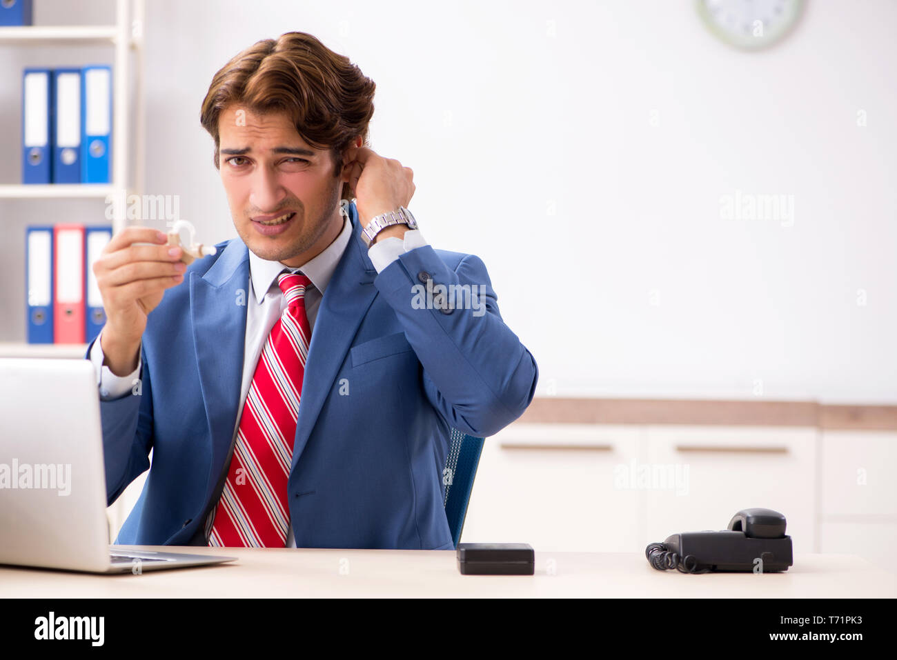 Deaf employee using hearing aid in office Stock Photo - Alamy
