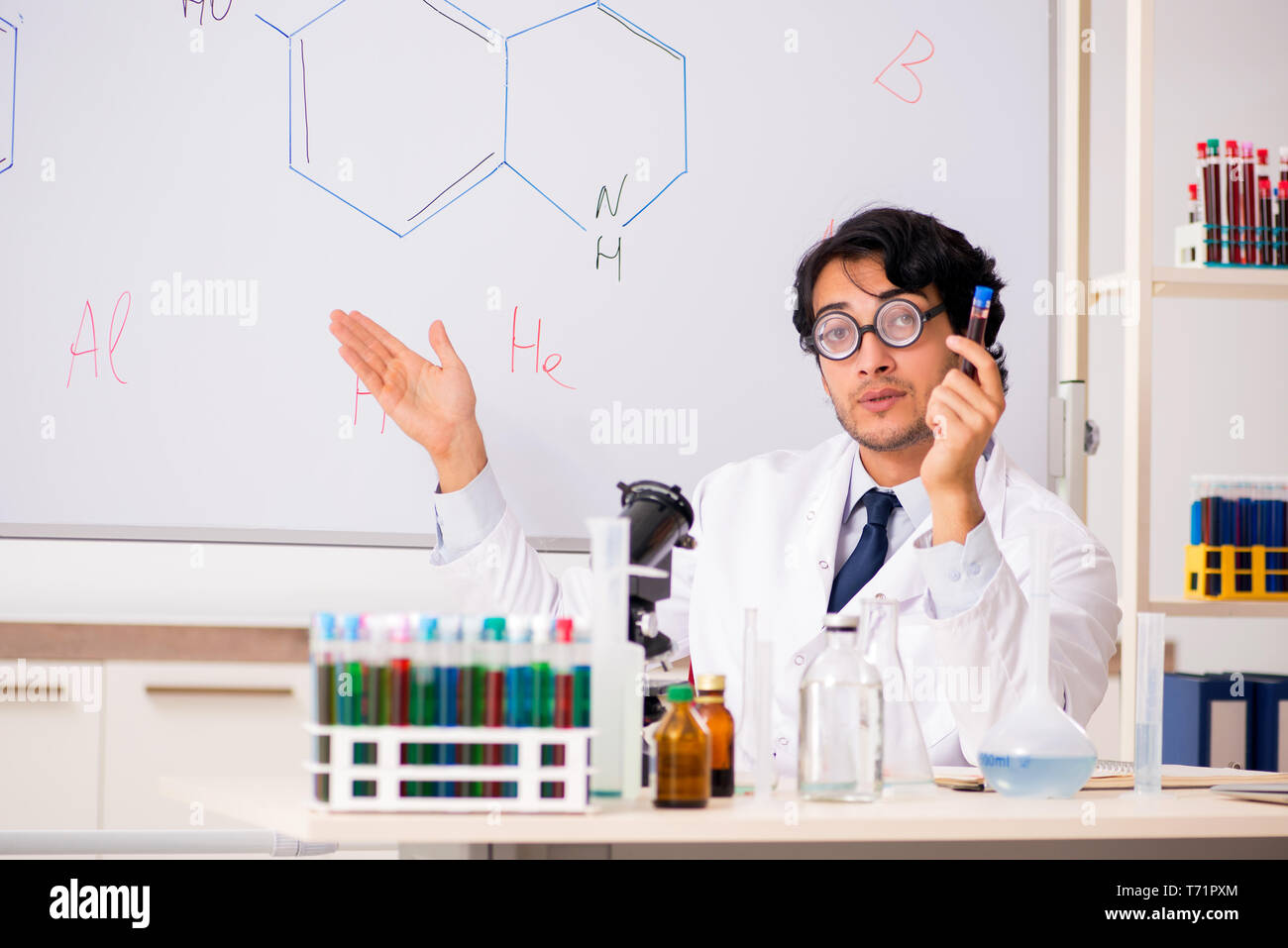 Young funny chemist in front of white board Stock Photo - Alamy
