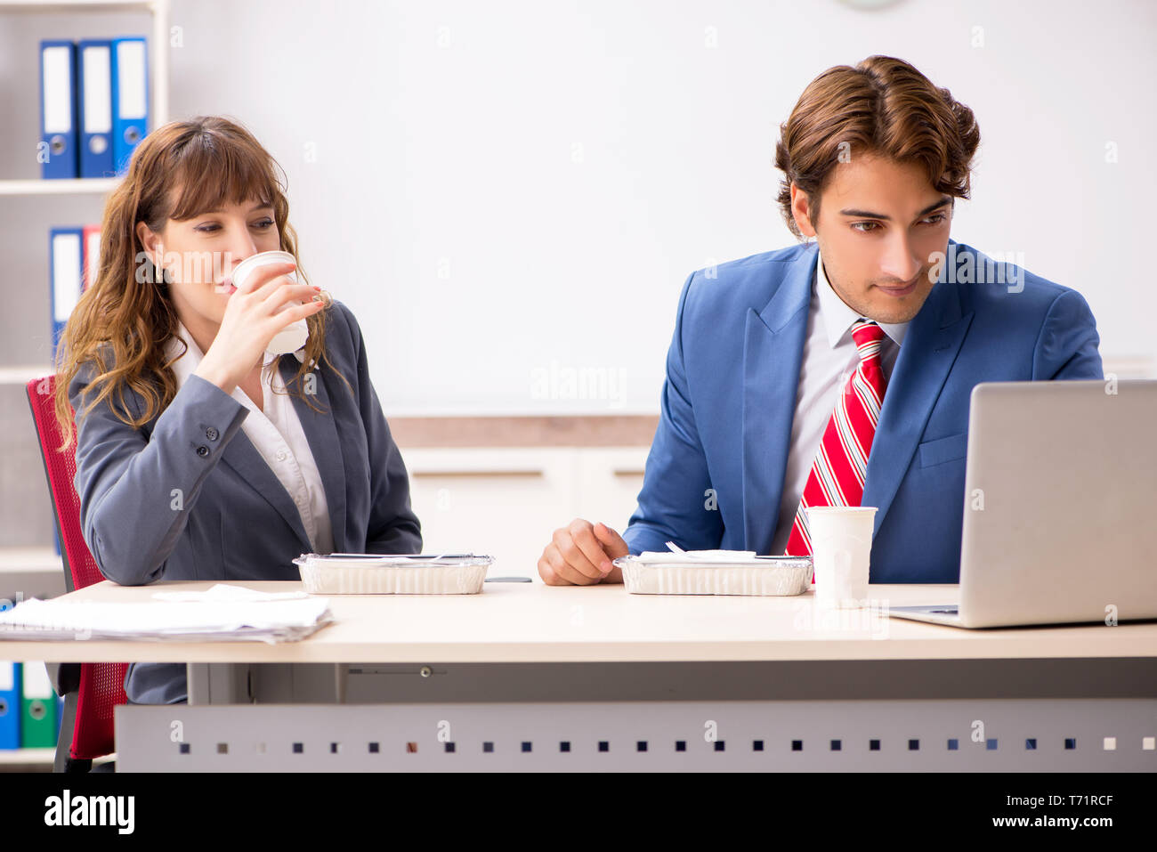 Two colleagues having lunch break at workplace Stock Photo - Alamy