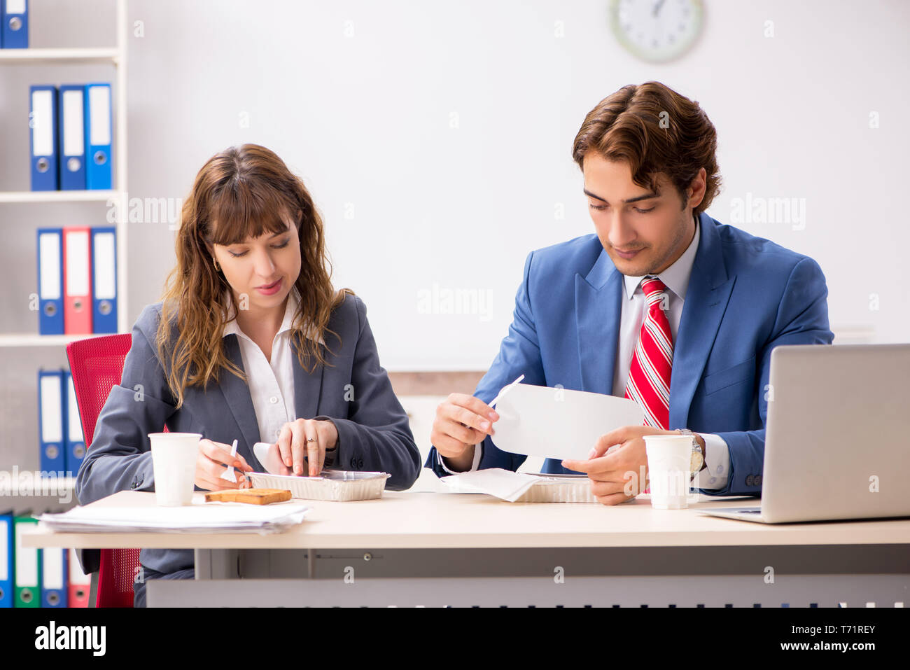 Two colleagues having lunch break at workplace Stock Photo - Alamy
