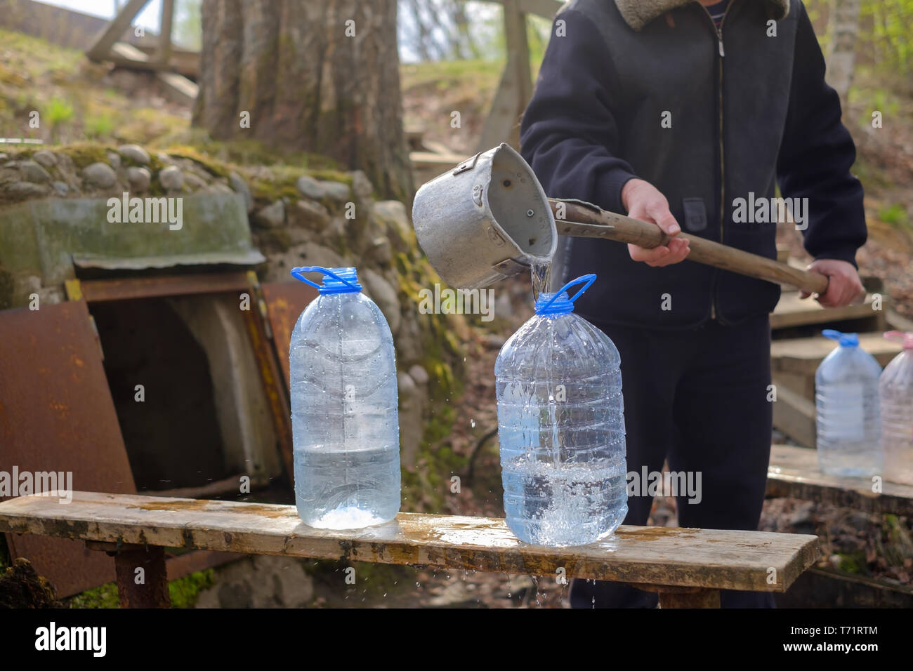 Caucasian man using scoop drawing water from old well Stock Photo - Alamy