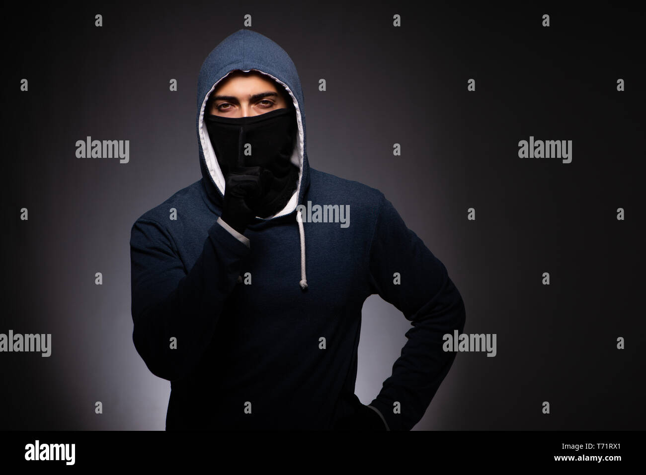 Young gangster in hood on grey background Stock Photo - Alamy