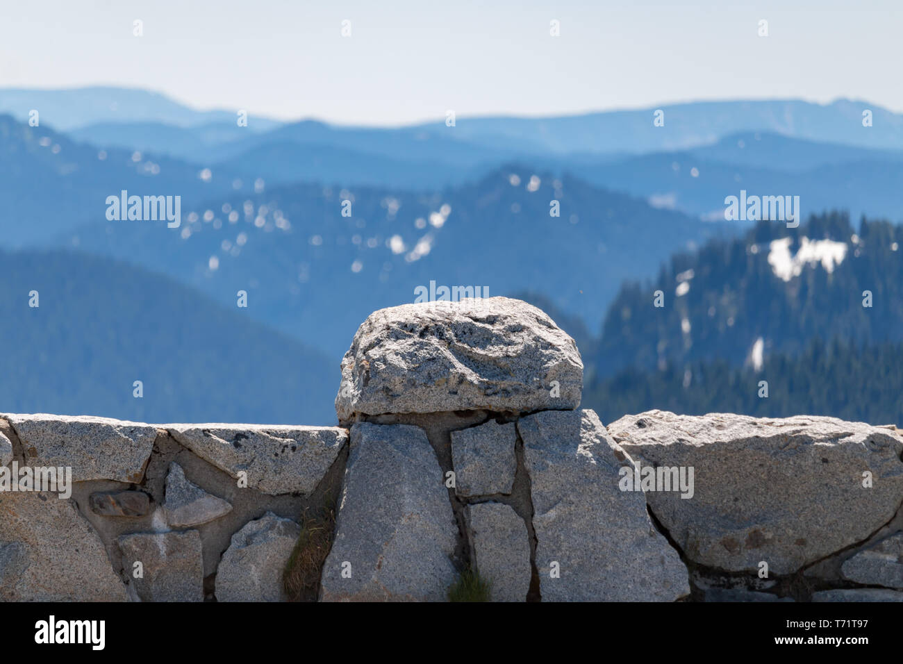 A low stone wall separates the road from a sheer dropoff with mountains ...