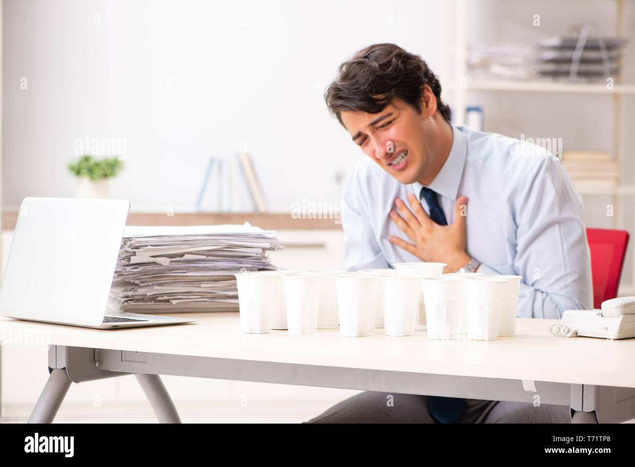 Young employee addicted to coffee Stock Photo - Alamy