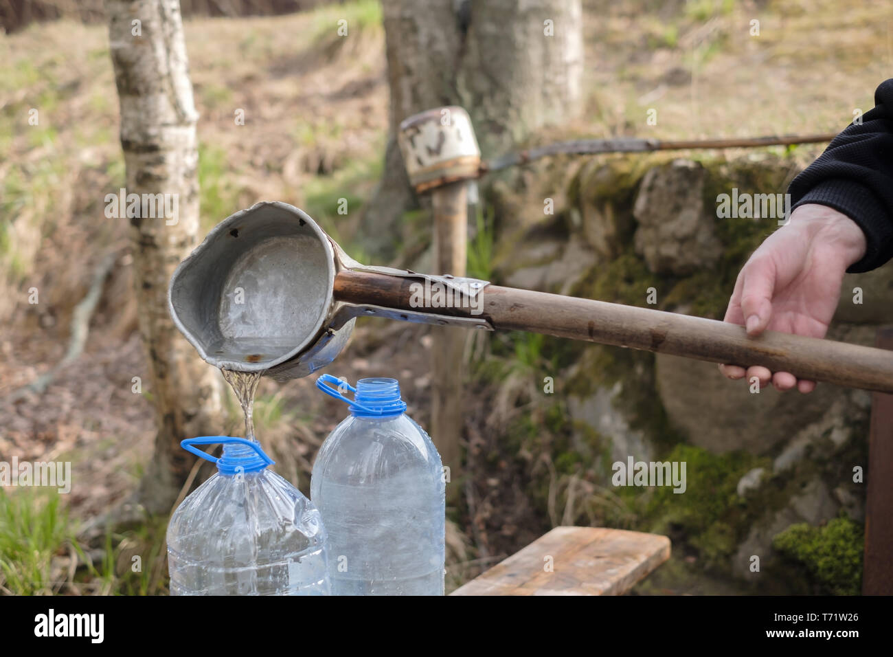 Caucasian man using scoop drawing water from old well Stock Photo - Alamy