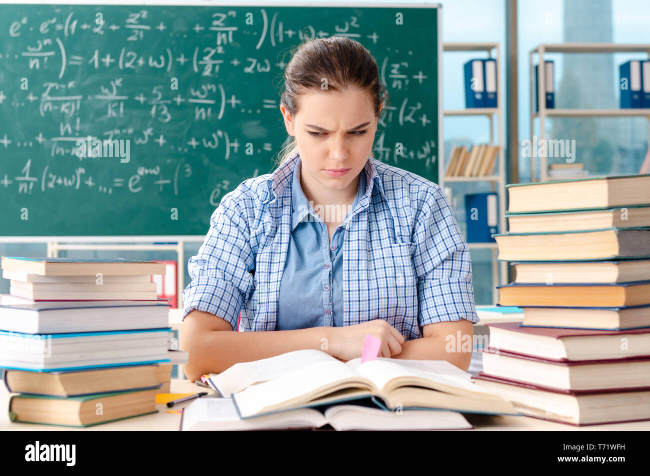 Female student with many books sitting in the classroom Stock Photo - Alamy