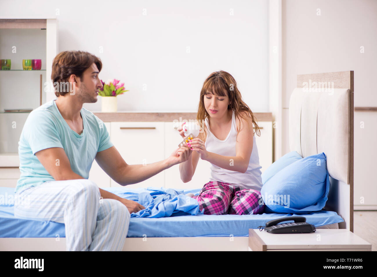 Young husband looking after sick wife in the bedroom Stock Photo - Alamy