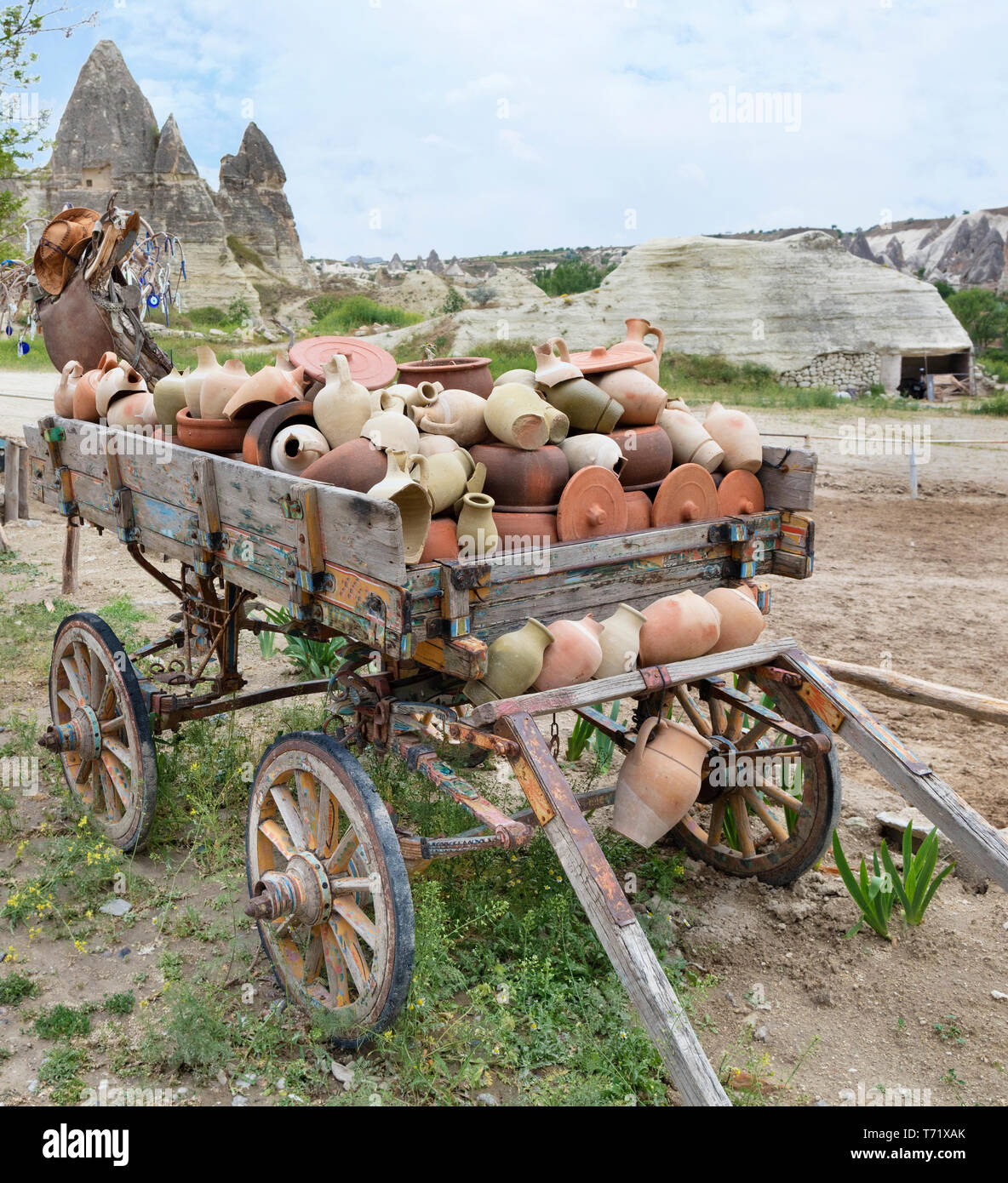 On an old wooden cart, a pile of clay jugs and pots is piled up against ...