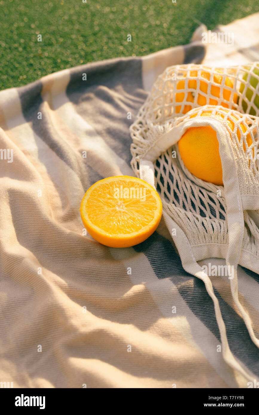 Fruit net bag on the plaid in the field Stock Photo - Alamy