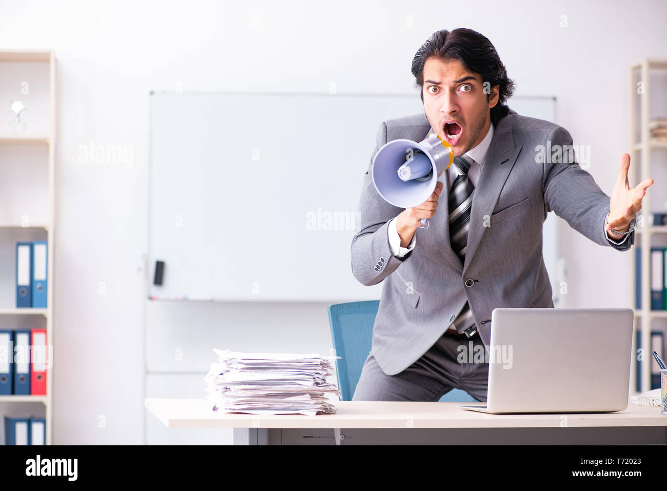 Young employee boss with megaphone in the office Stock Photo - Alamy