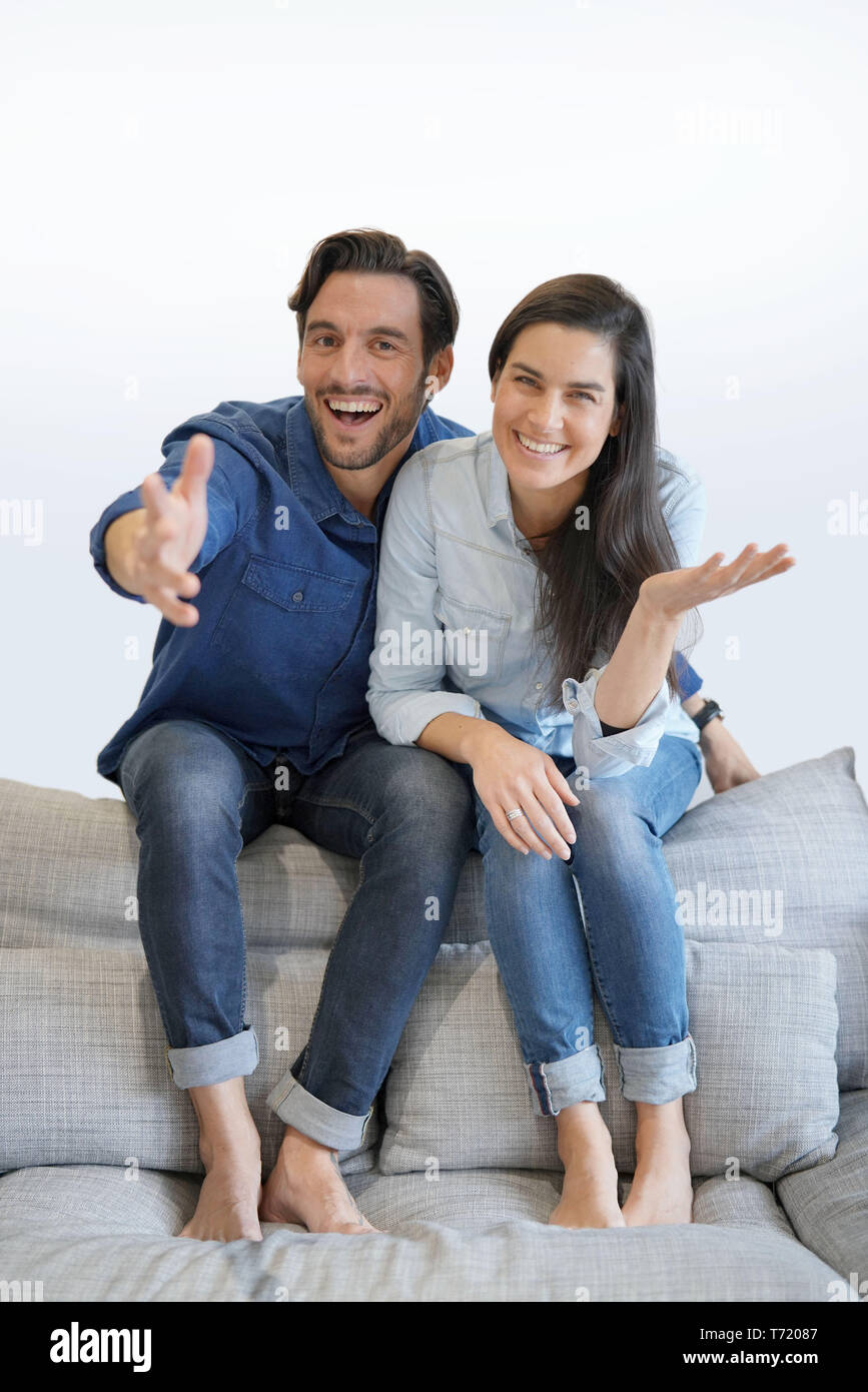 Isolated gorgeous smiling couple in denim on comfy couch Stock Photo ...