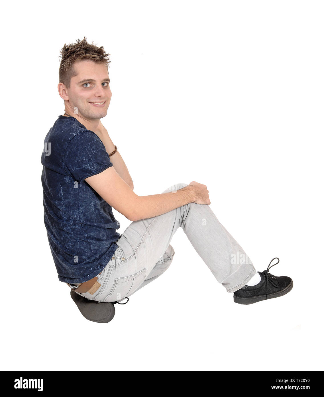 Happy young man sitting on the floor Stock Photo - Alamy