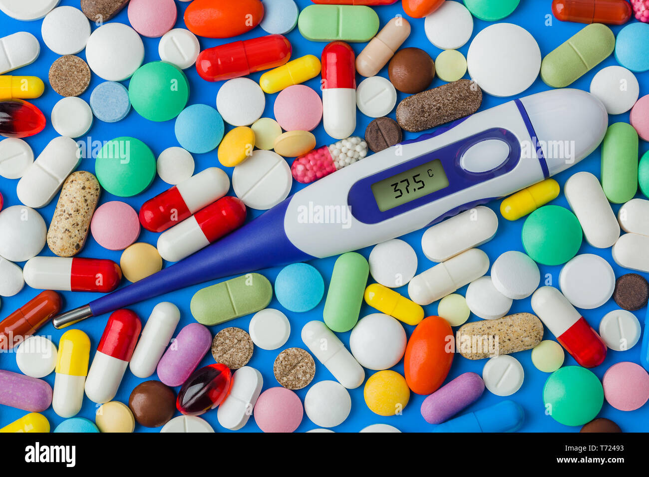 Pills and electronic thermometer (37.5 degrees) - medical background ...