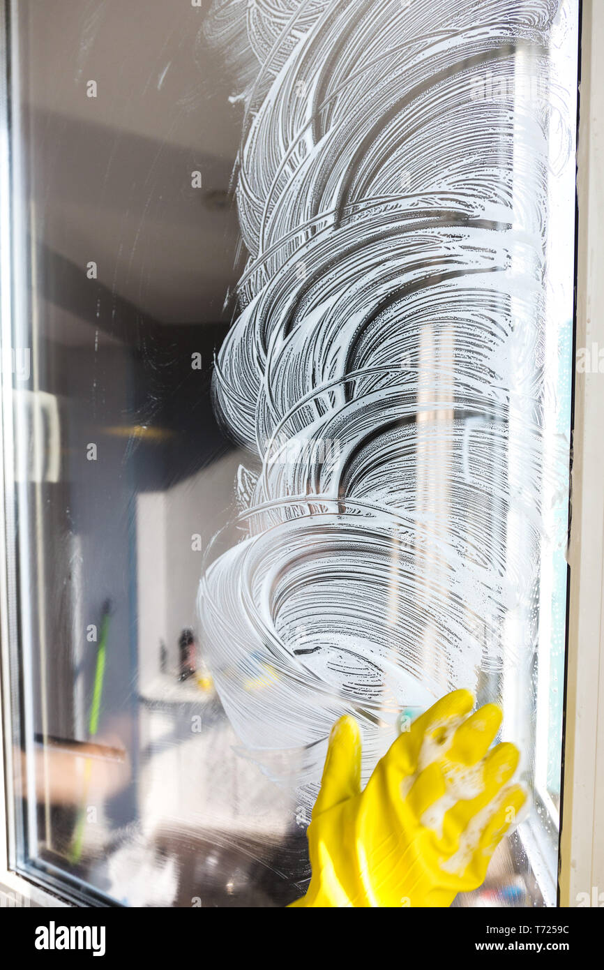 Close-up of a woman in uniform and yellow gloves washes a windows with ...