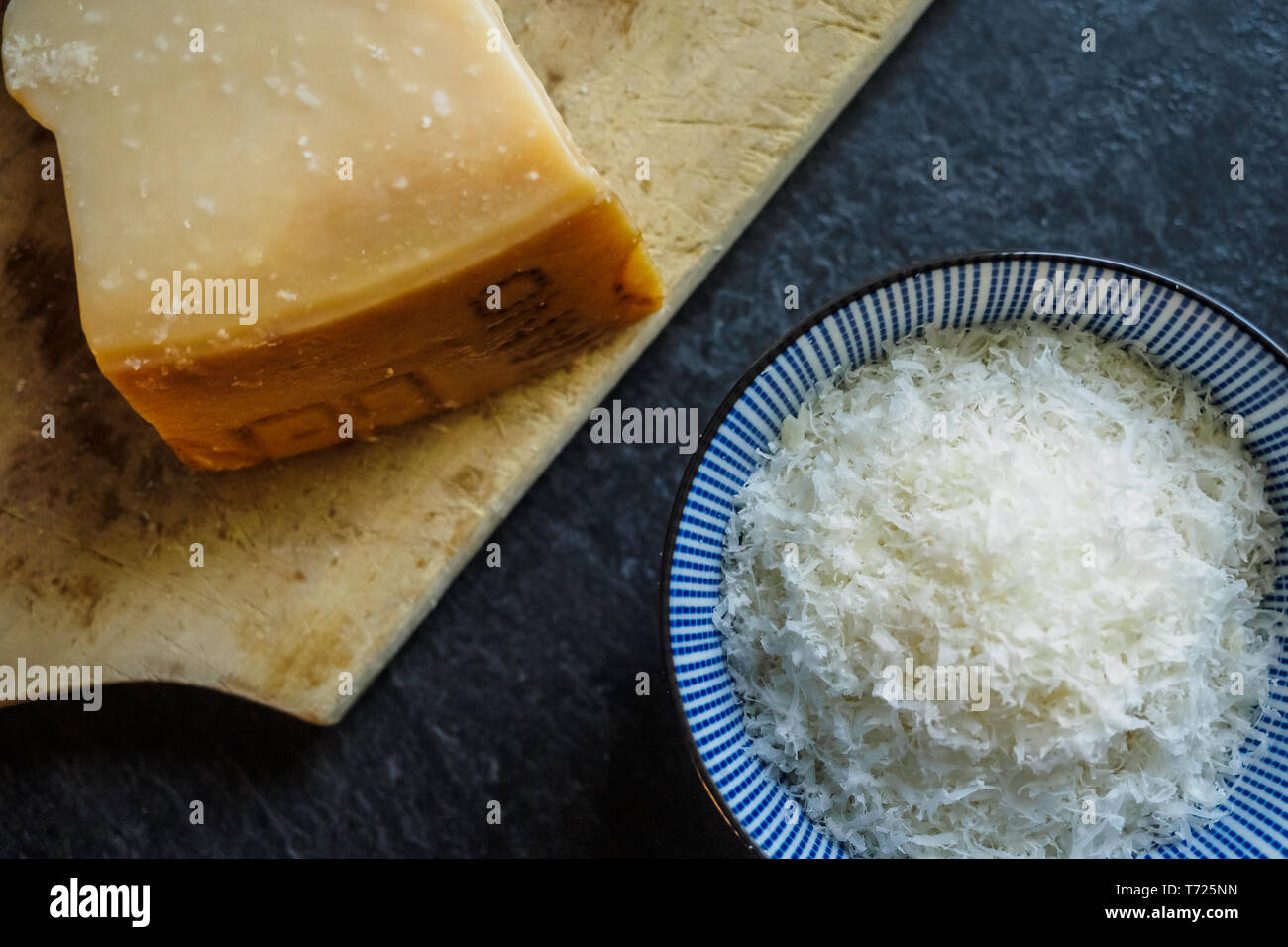 Grated parmesan cheese in a bowl on black background, italian food ...