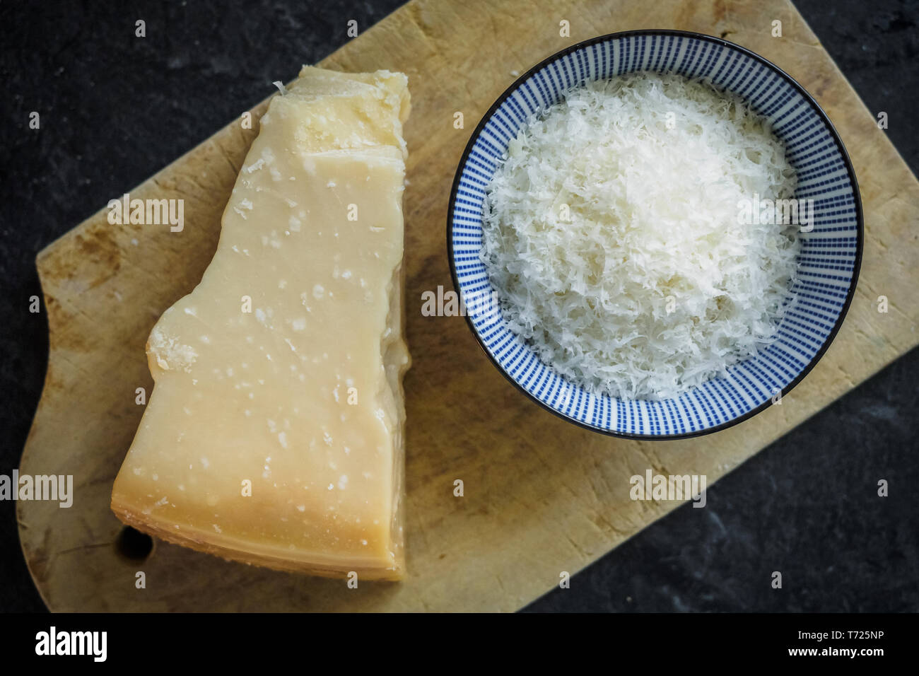 Grated parmesan cheese in a bowl on black background, italian food ...