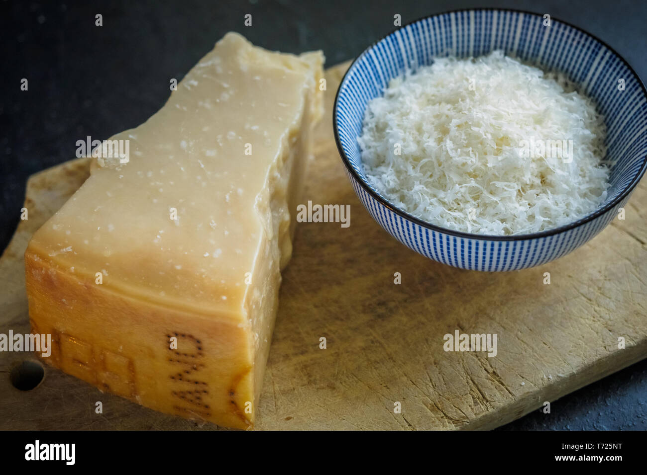 Grated parmesan cheese in a bowl on black background, italian food ...