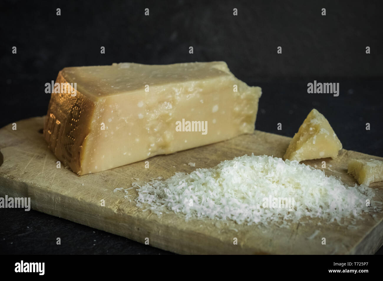 Grated parmesan cheese on black background, italian food. Dark food ...