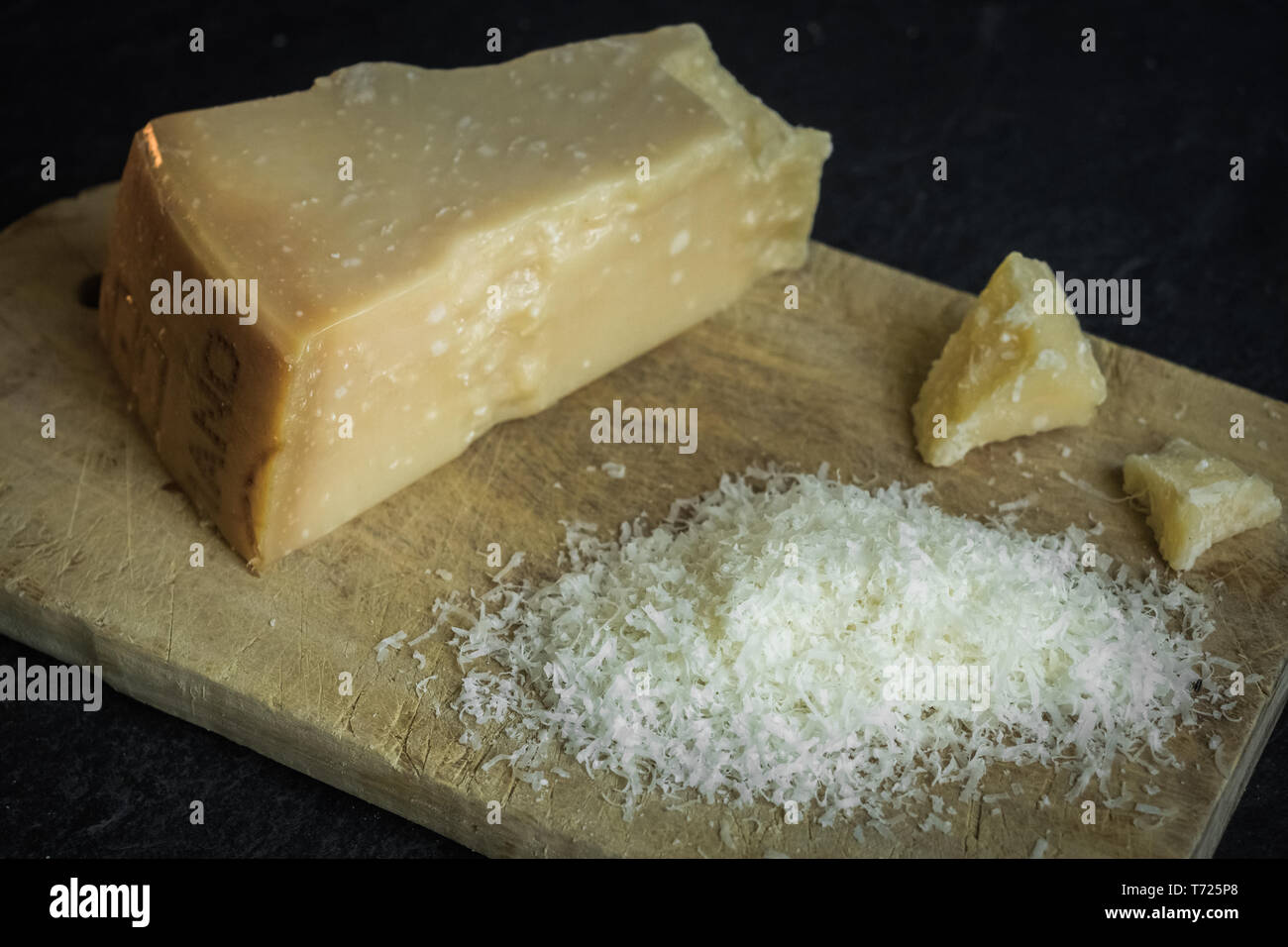 Grated parmesan cheese on black background, italian food. Dark food ...