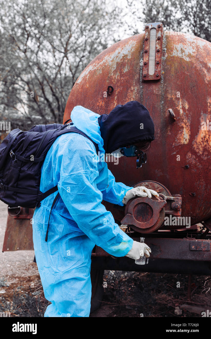 Men in blue protective overall at the old destroyed factory testing ...