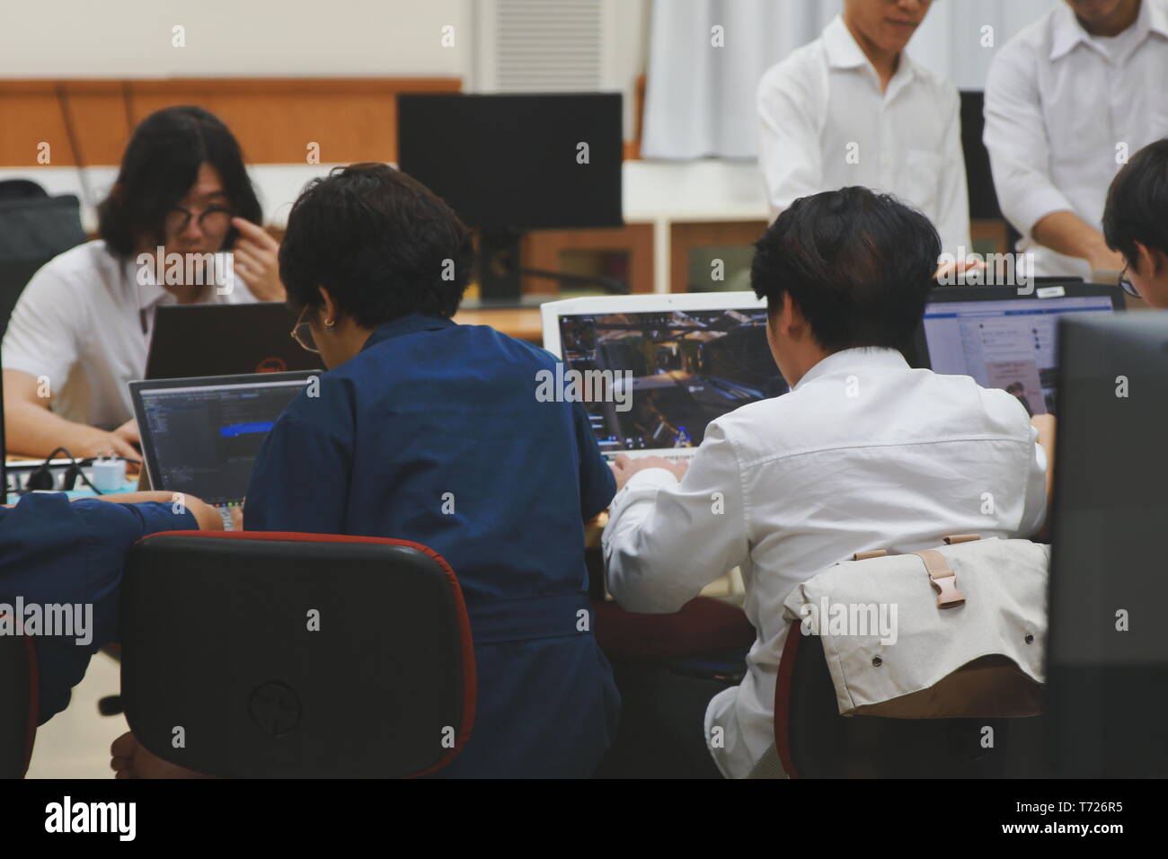 Asian university student playing game on his laptop in the classroom ...