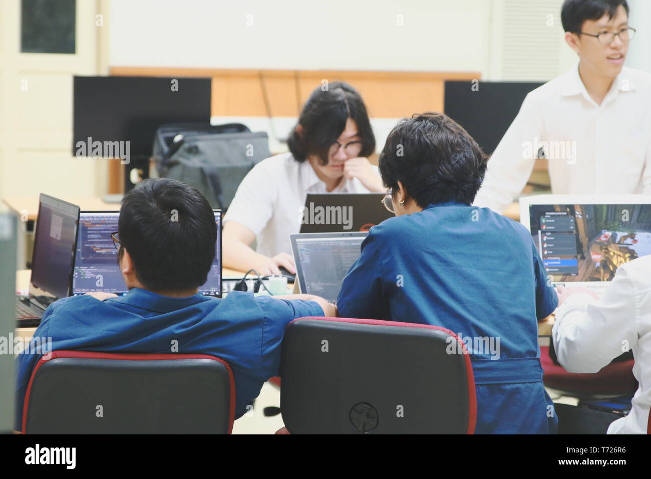 Asian university student playing game on his laptop in the classroom ...