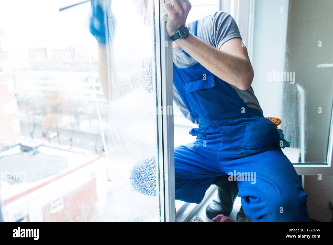 Close-up of a man in uniform and blue gloves washes a windows with ...