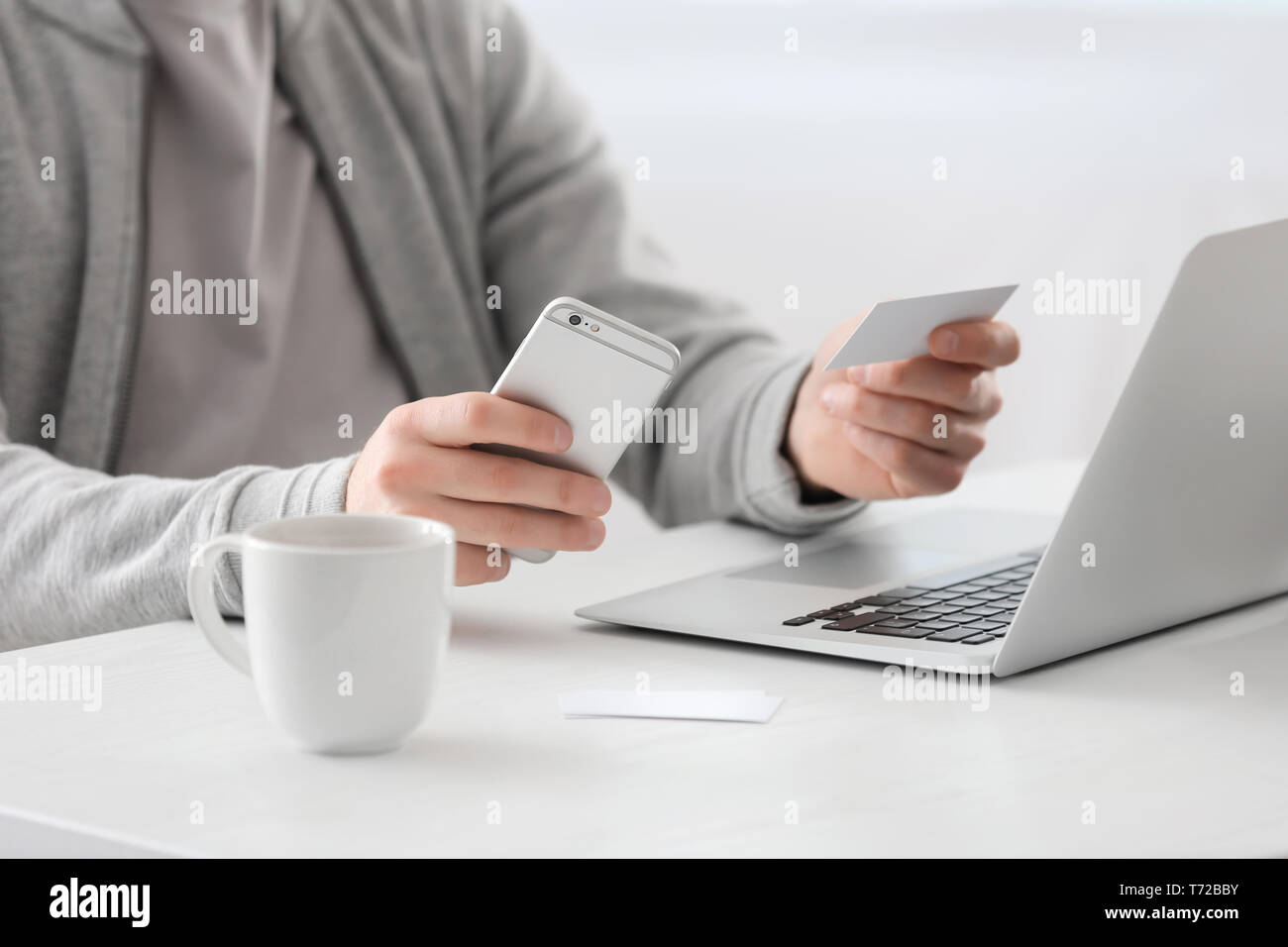 Male freelancer with smartphone and business card at workplace Stock Photo - Alamy