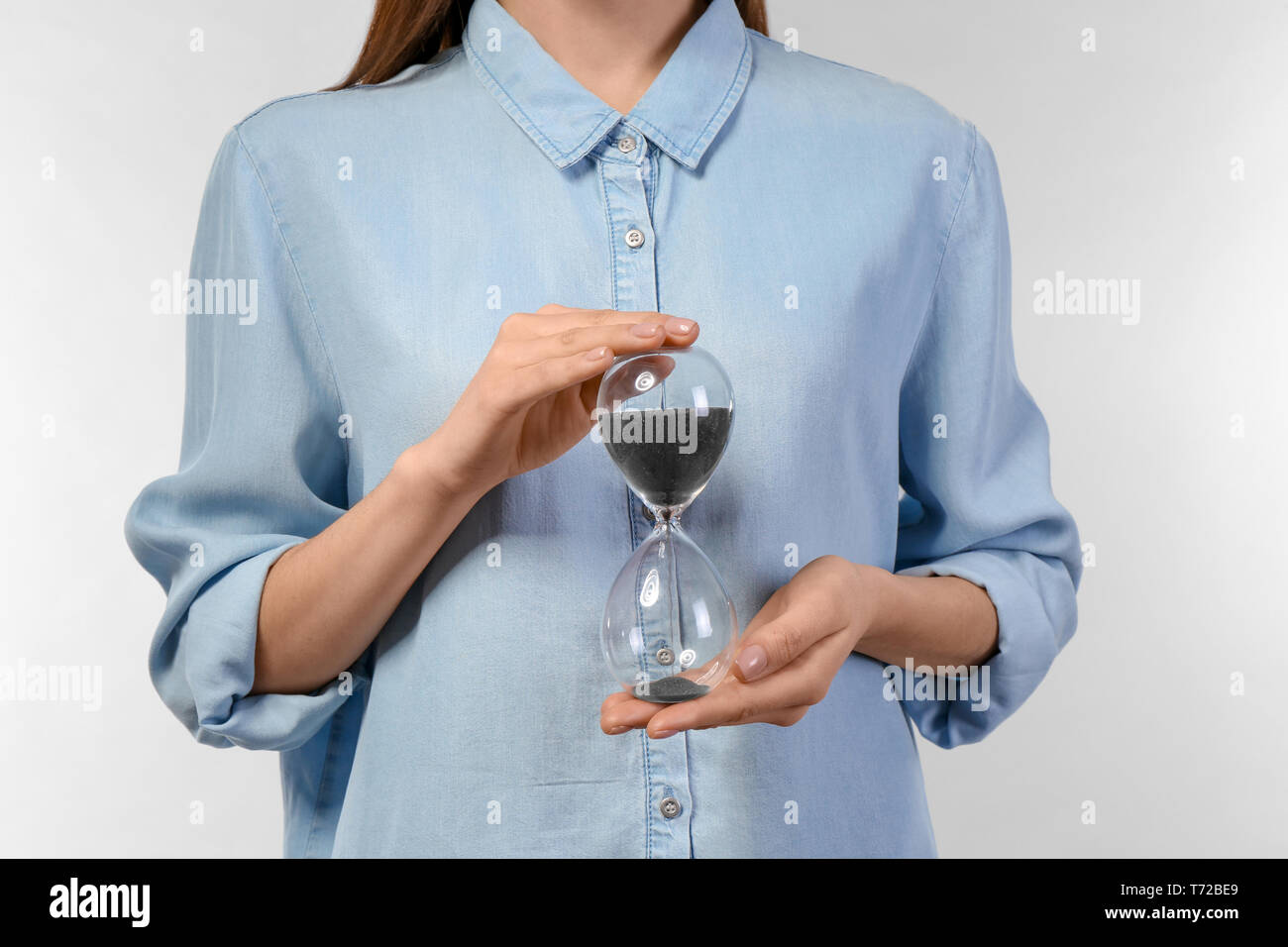 Woman holding hourglass on light background. Time management concept ...