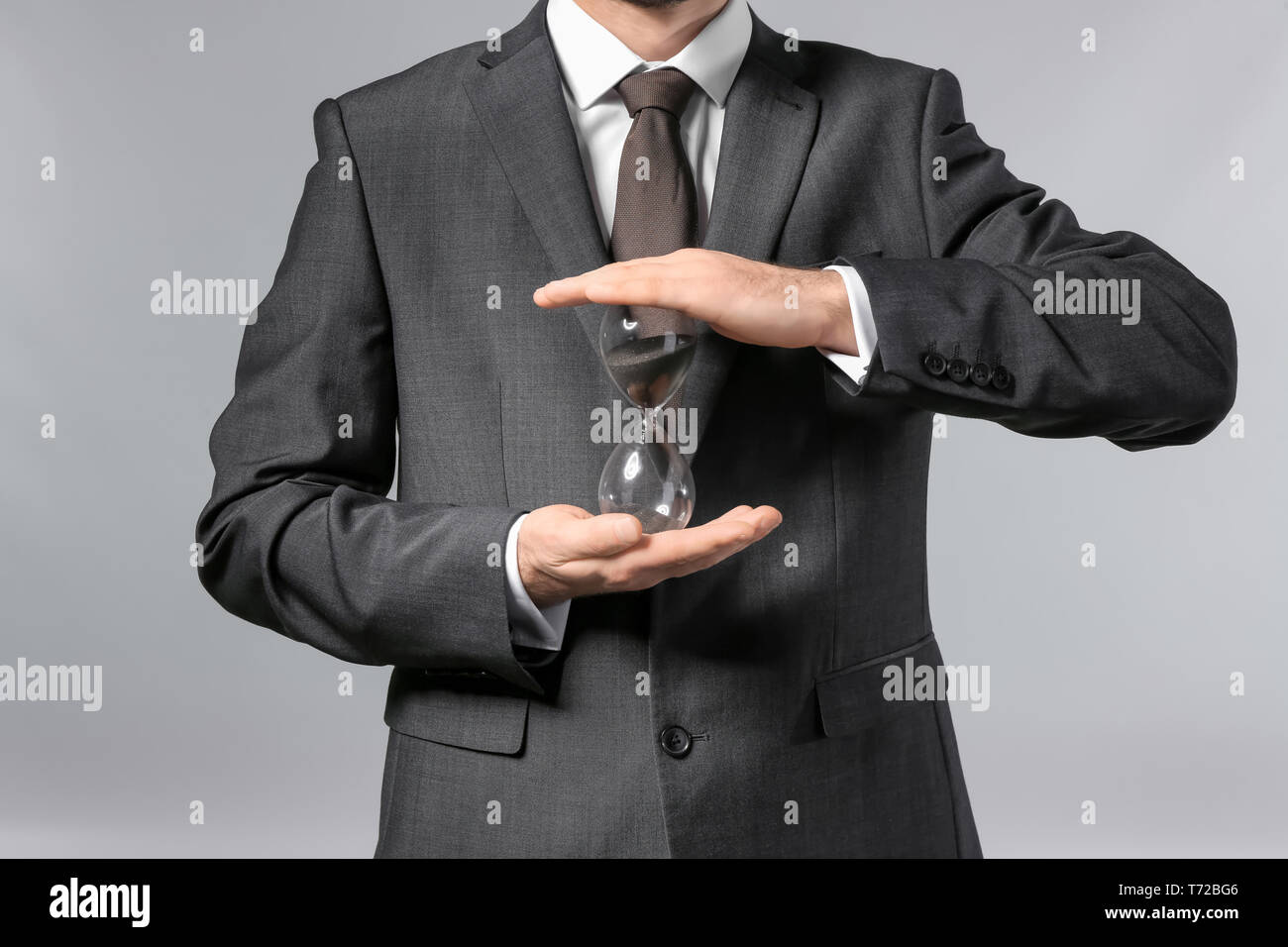 Man holding hourglass on grey background. Time management concept Stock ...