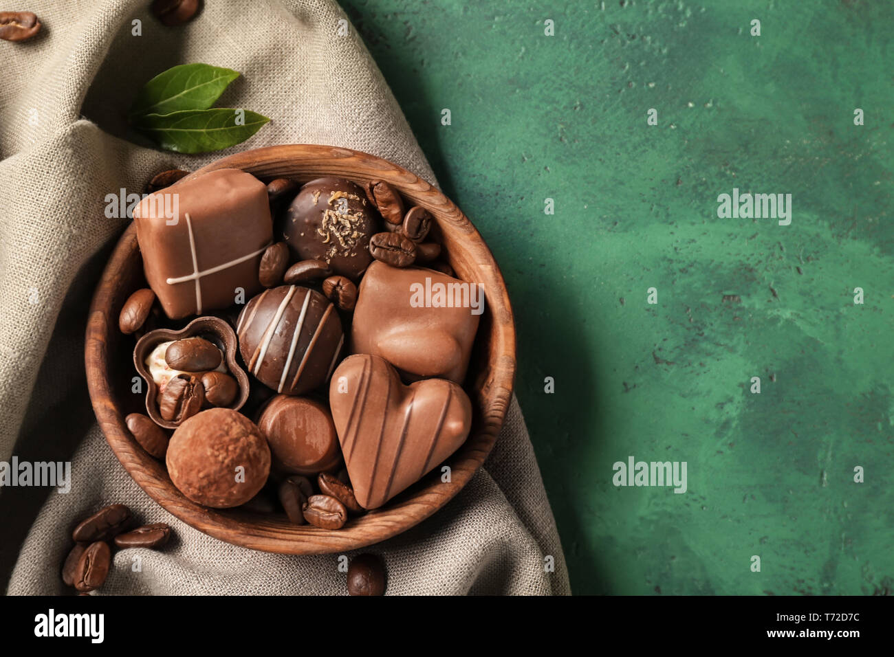 Bowl with different tasty chocolate candies on textured table Stock ...
