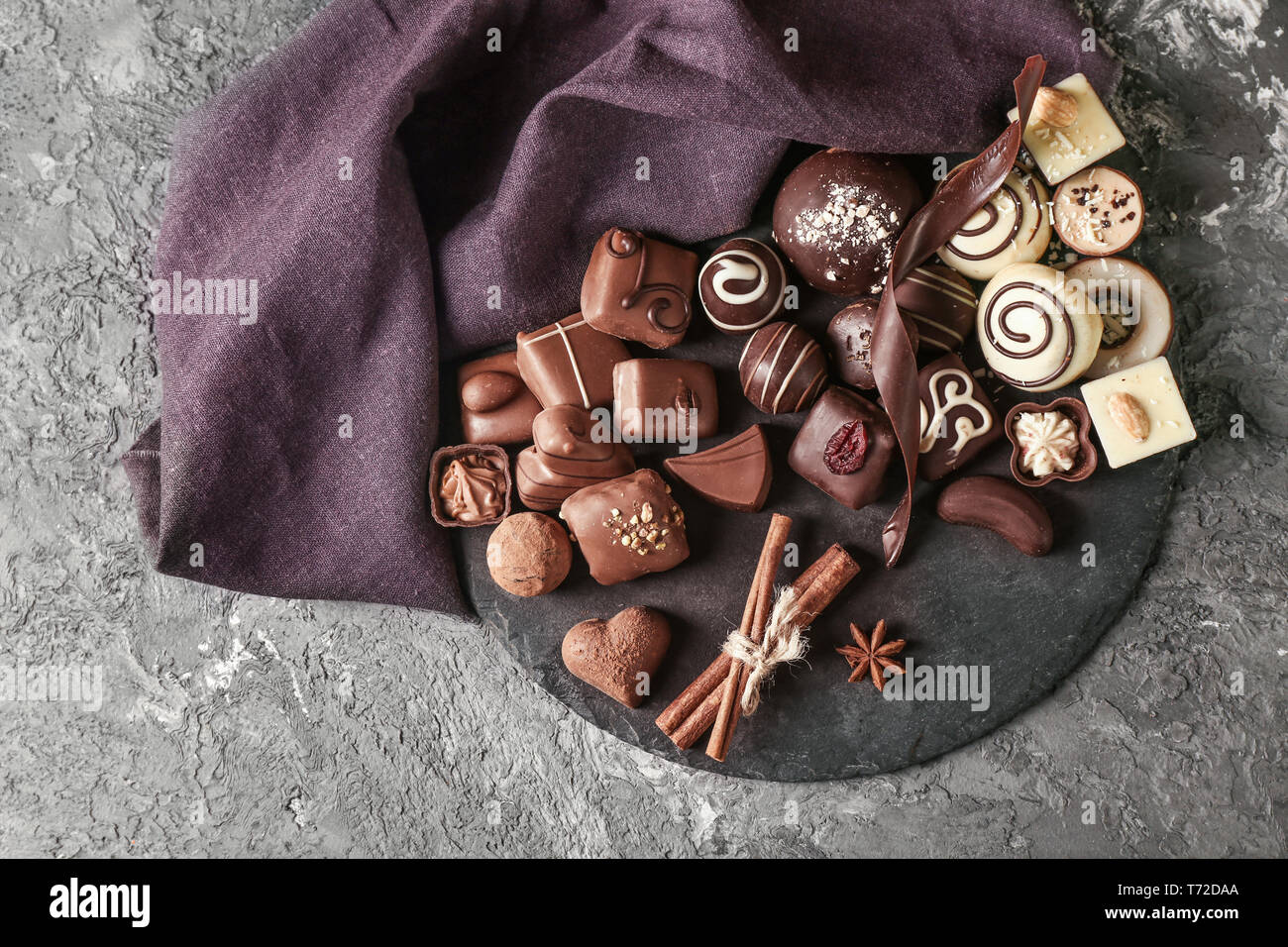 Slate plate with different tasty chocolate candies on textured table ...