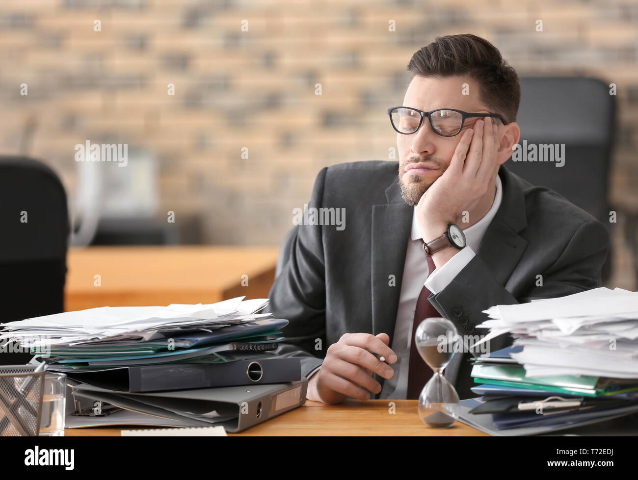 Tired mature businessman at table in office. Time management concept ...