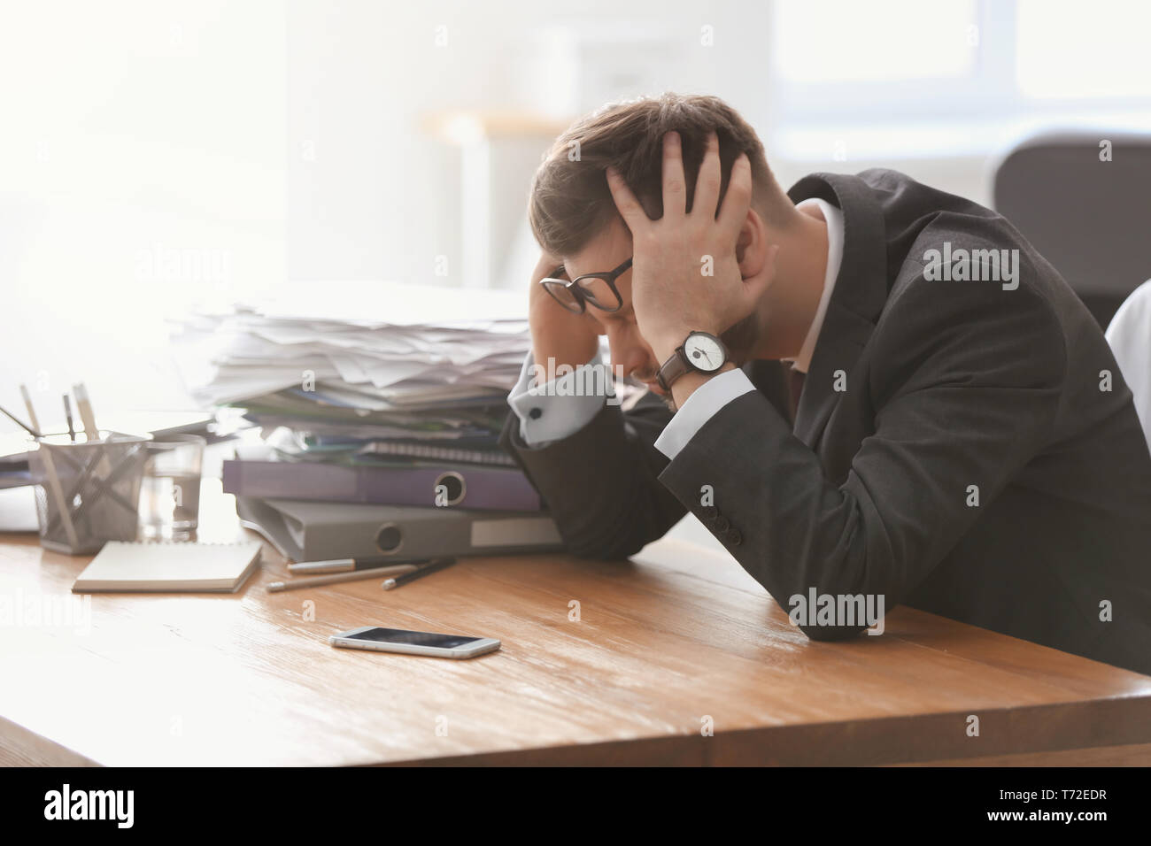 Tired mature businessman at table in office. Time management concept ...