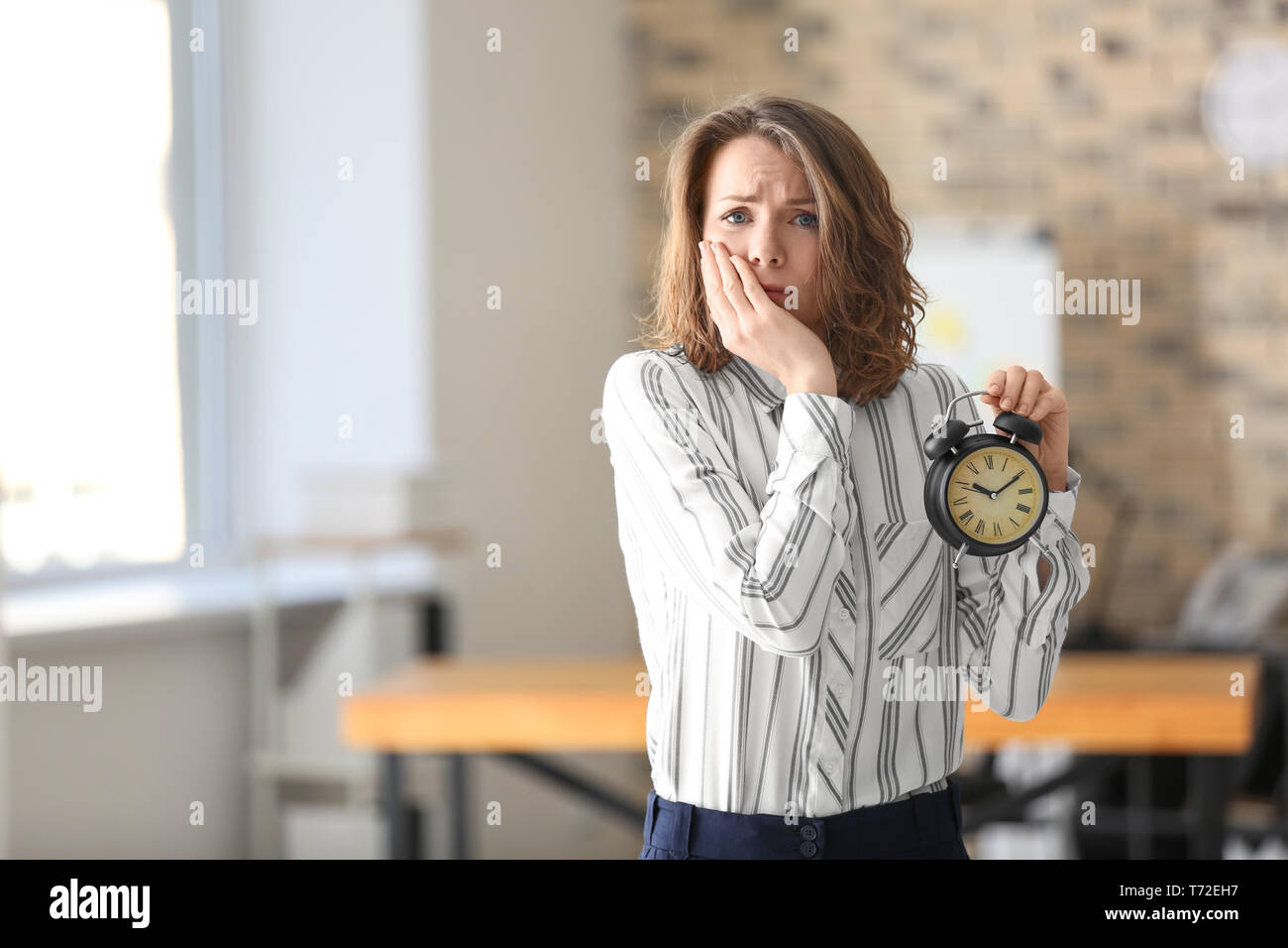 Mature woman with alarm clock in office. Time management concept Stock ...