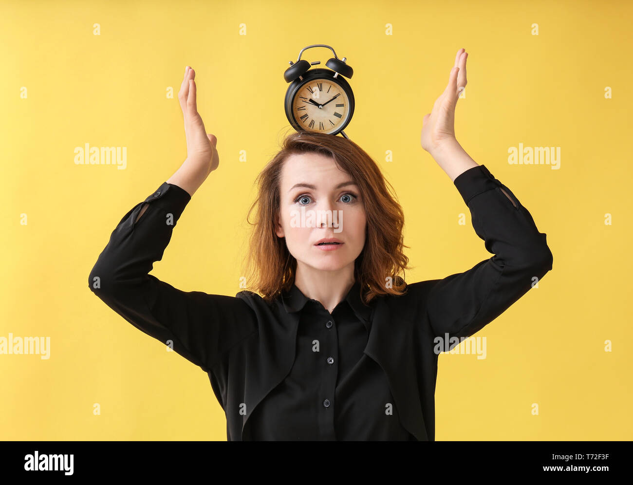 Mature woman with alarm clock on head against color background. Time ...