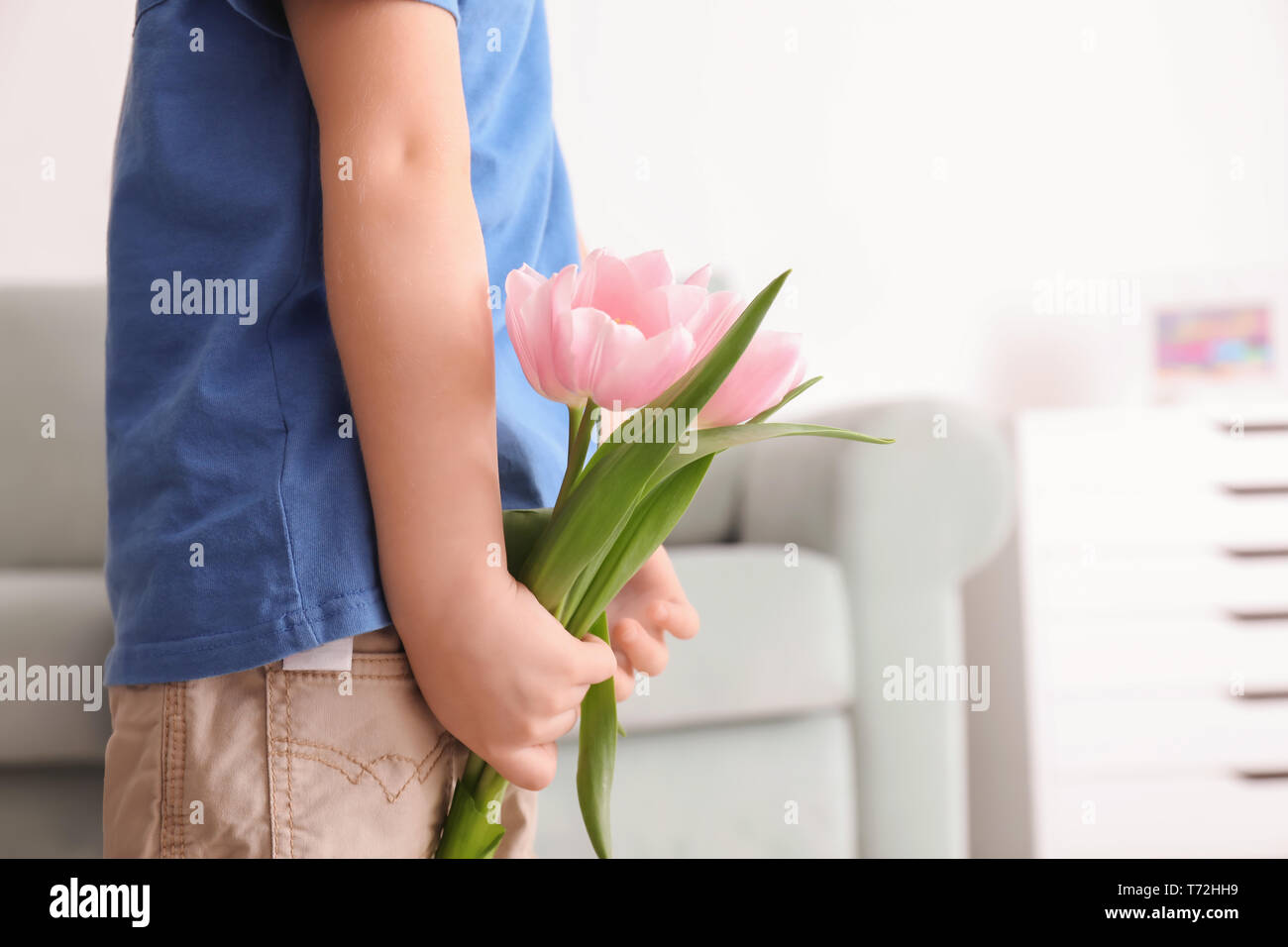 Cute little boy hiding flowers behind his back at home Stock Photo - Alamy