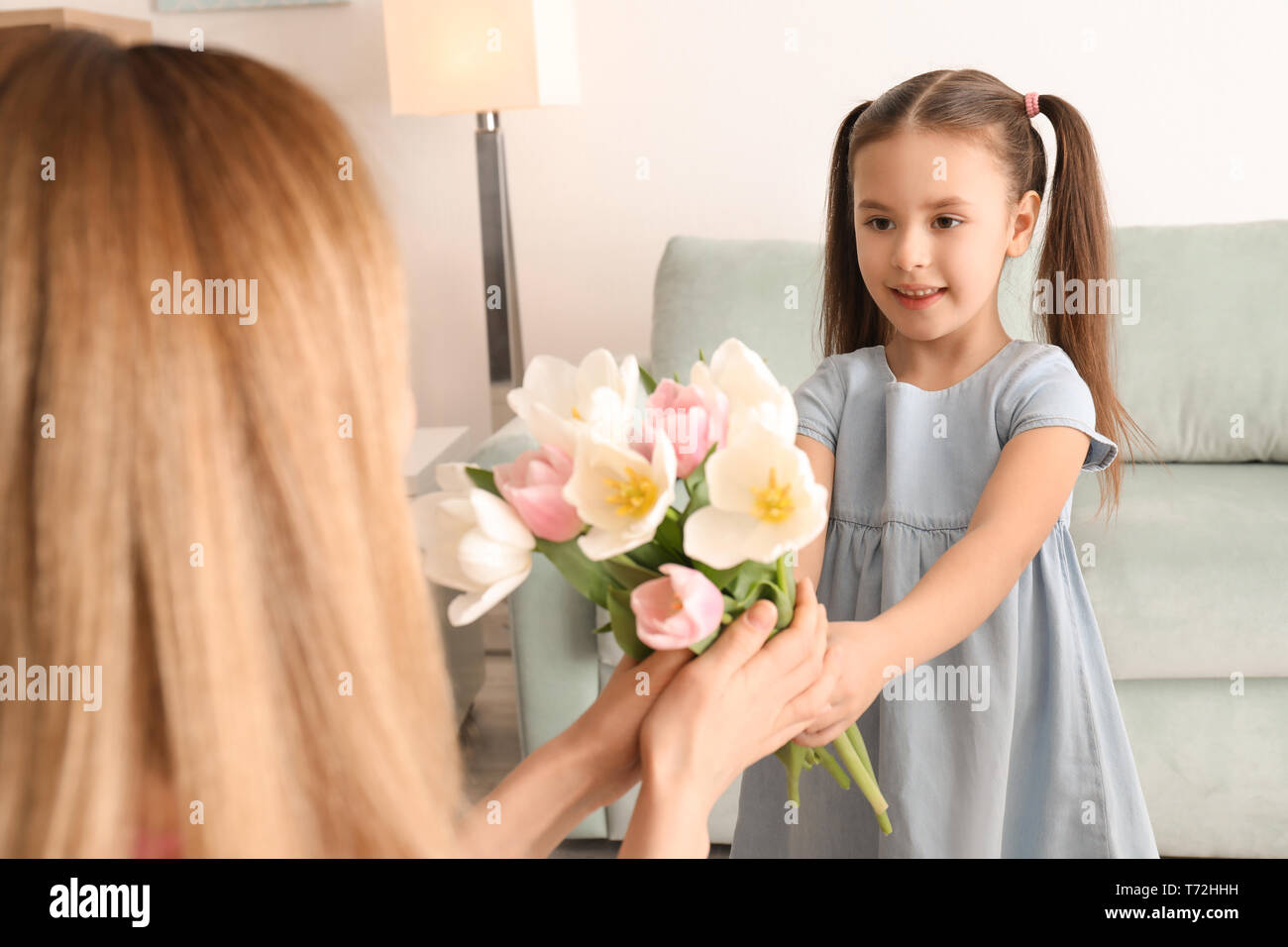 Mother receiving flowers from her cute little daughter at home Stock ...