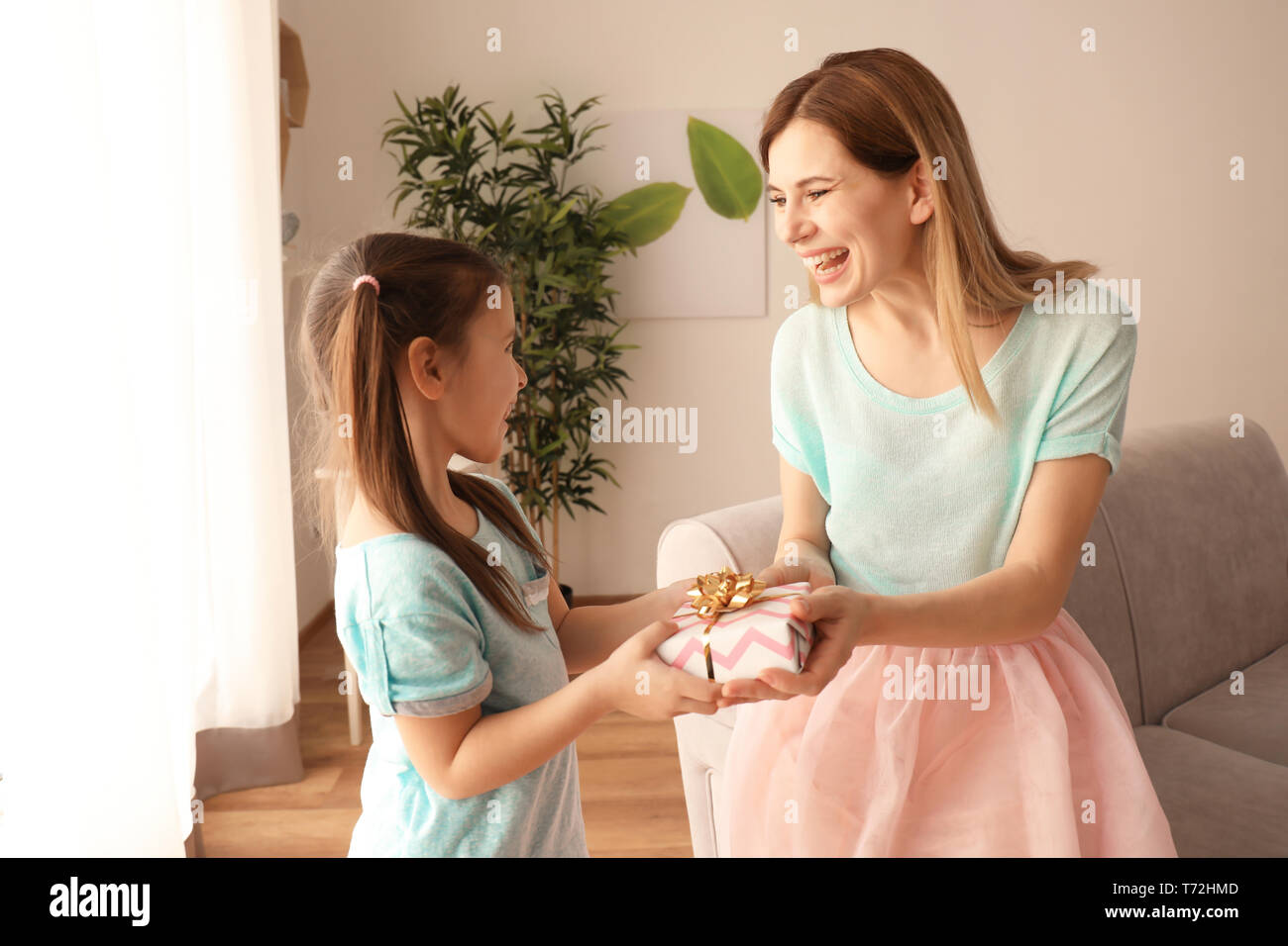 Mother receiving gift from her cute little daughter at home Stock Photo ...