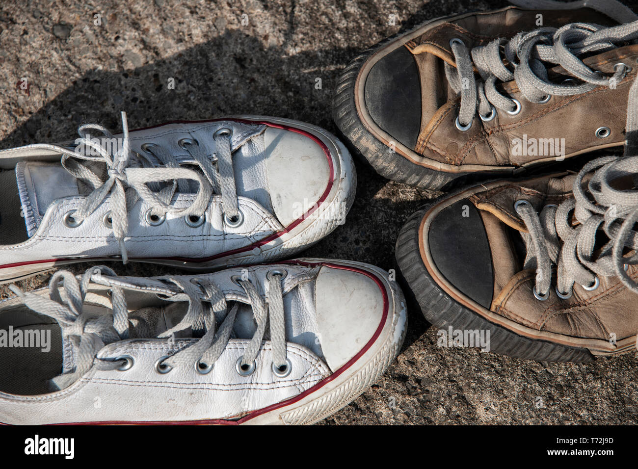 Pairs of men's and women's sneakers standing toe to toe on a concrete ...