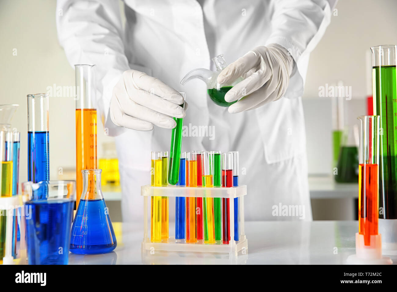 Laboratory assistant pouring liquid into test tube over table Stock ...