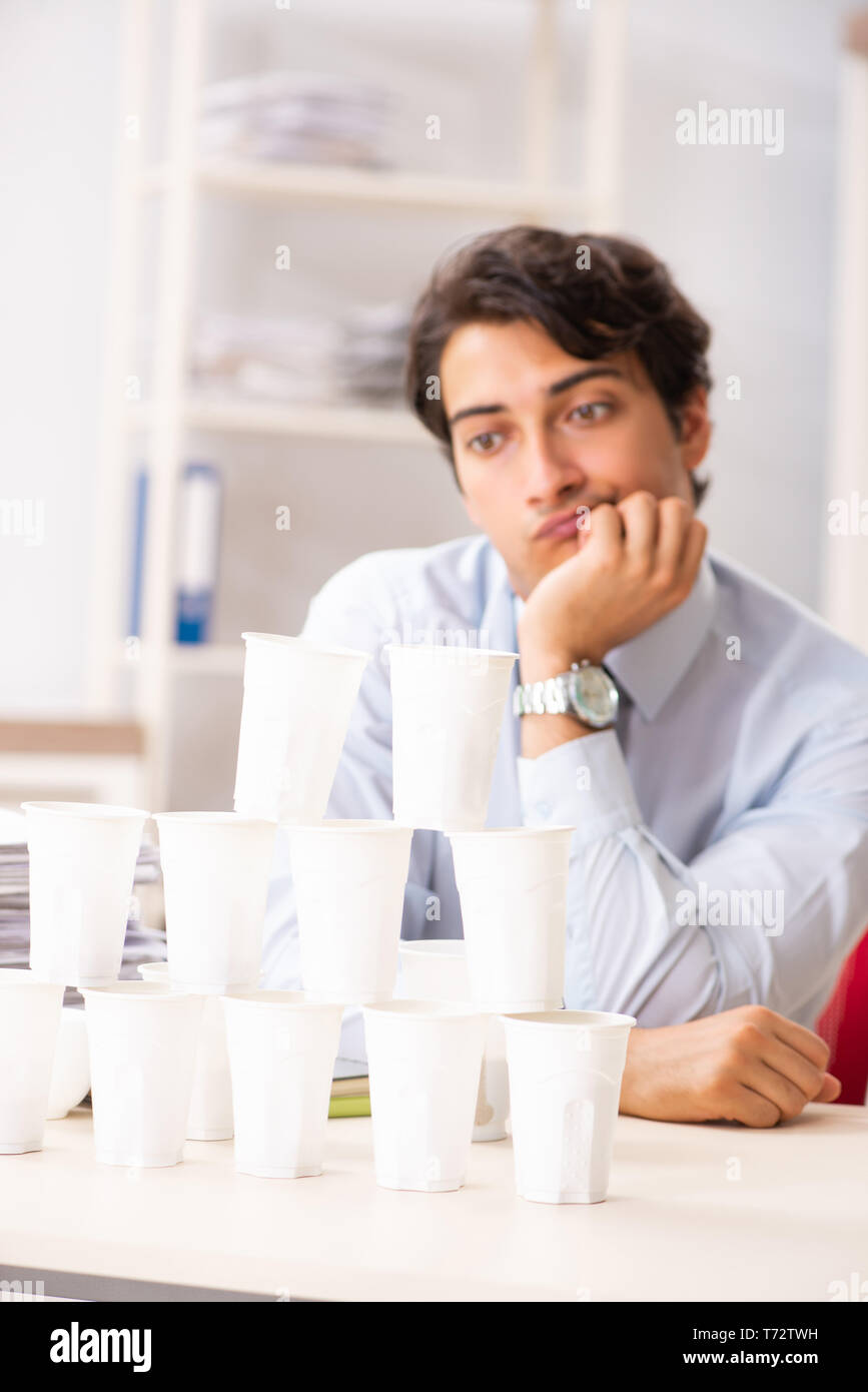 Young employee building pyramid from plastic cups Stock Photo - Alamy