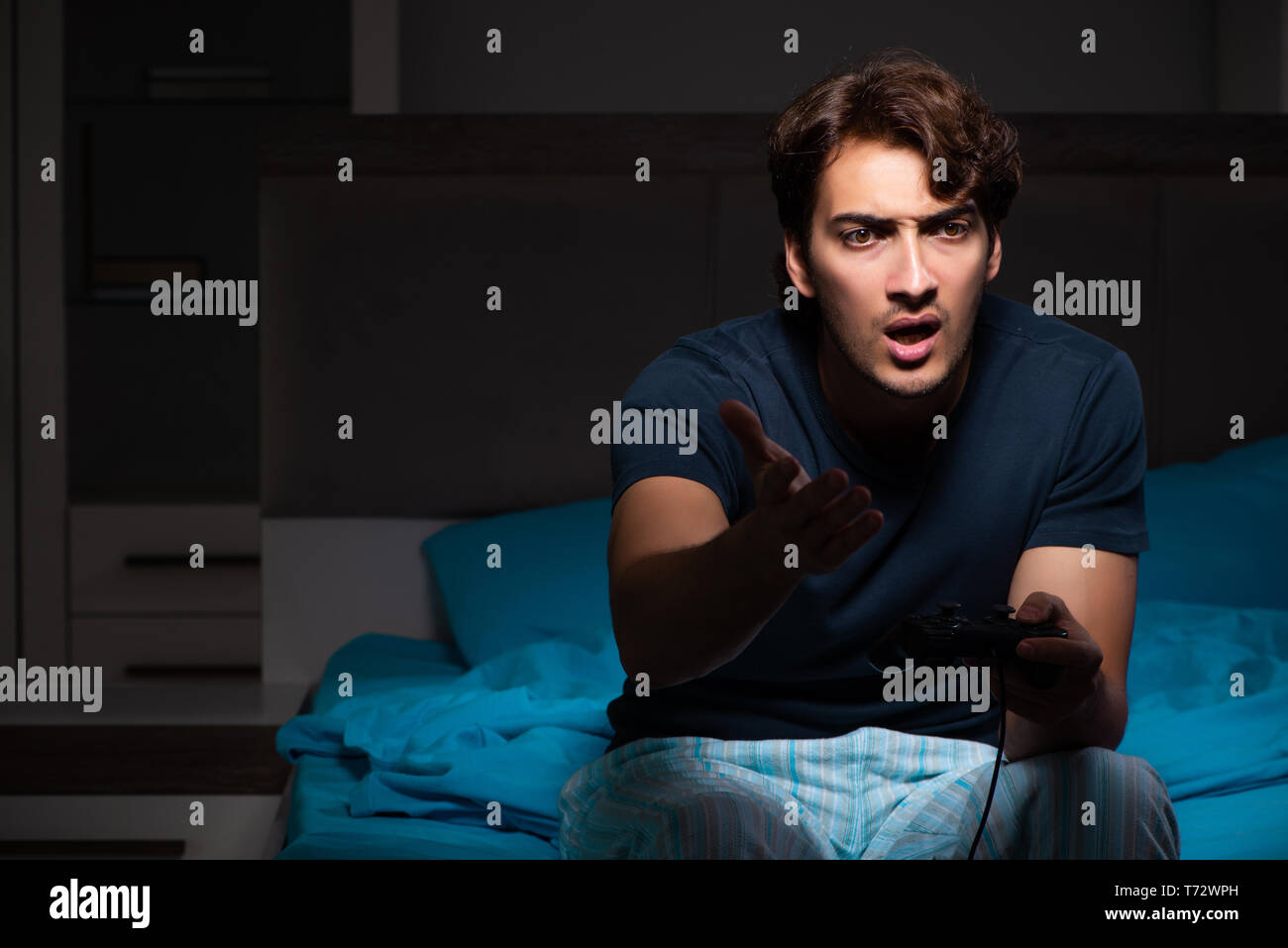 Young man playing computer games at night in bed Stock Photo - Alamy
