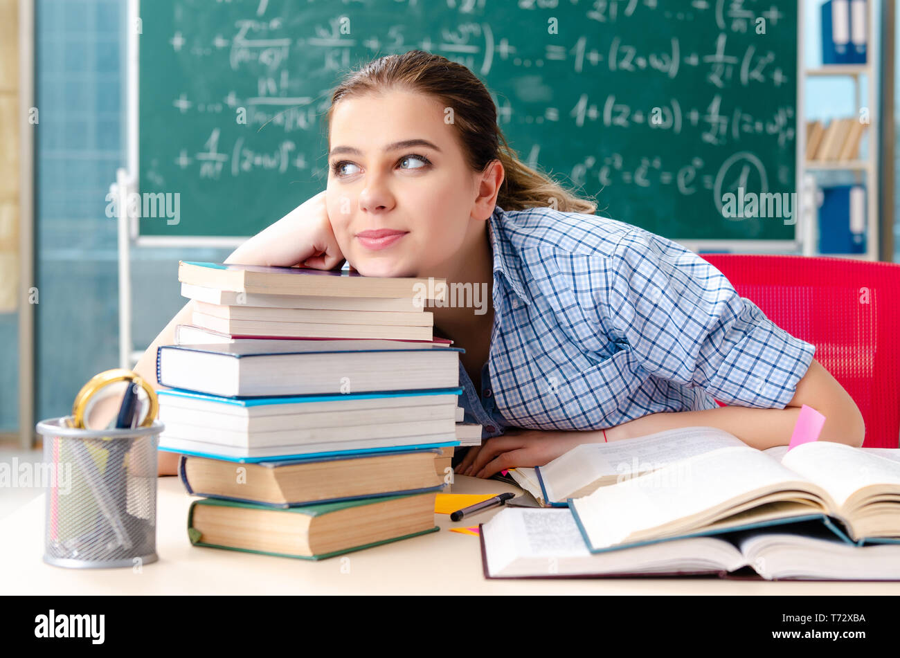 Female student with many books sitting in the classroom Stock Photo - Alamy